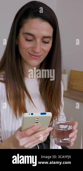 Vertical HD video of young woman drinking water and using smartphone in ...