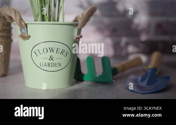 A green pot labeled flowers and garden holds fresh plants alongside ...