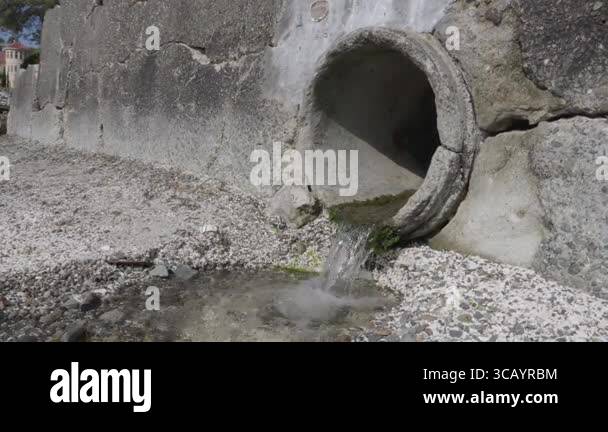 Water Flowing from Algae Covered Drain Pipe. Side shot of water pouring ...