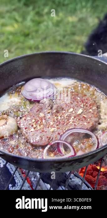 Vertical video. Food preparation. Frying steak in a cast iron pan on ...