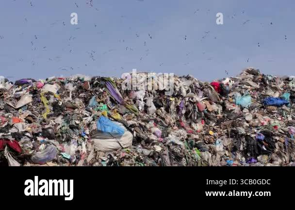 A massive accumulation of discarded plastic and debris towers over a ...