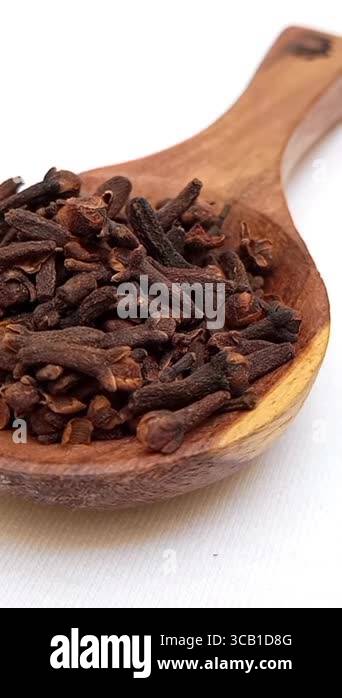 Whole Cloves in a wooden spoon rotating on white background, herbs and ...