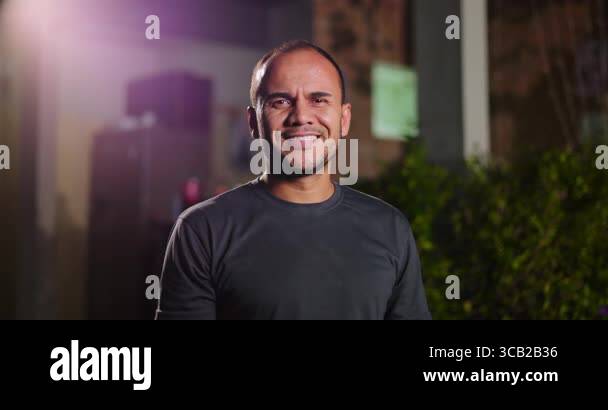 Latin Hispanic man smiling confidently outdoors at night, standing in ...