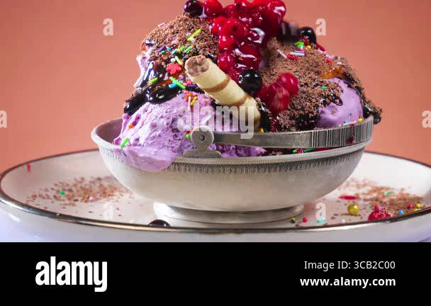 Sweet ice cream in a metal, silver container slowly rotates around its ...