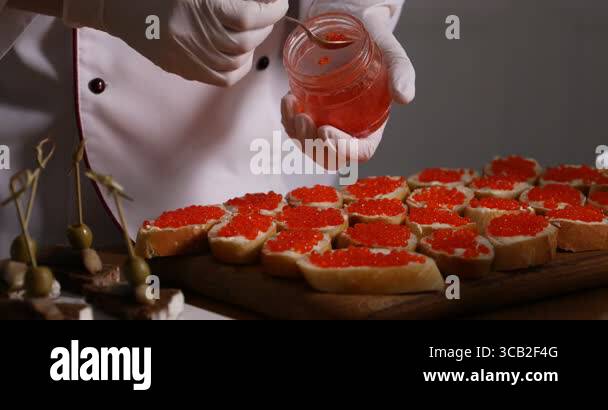 Chef making sandwiches with red caviar for buffet at table indoors ...