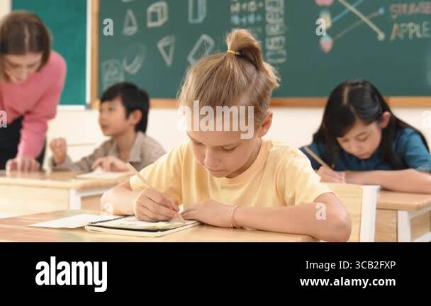 Caucasian smart child smiling at camera while doing classwork at ...