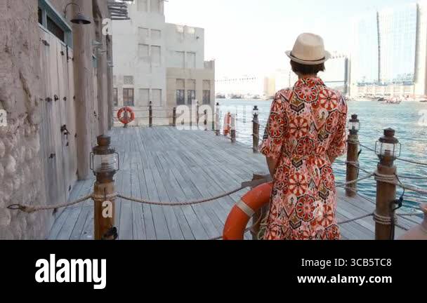 Young woman in ethnic dress and hat exploring Al Seef Park in Dubai ...