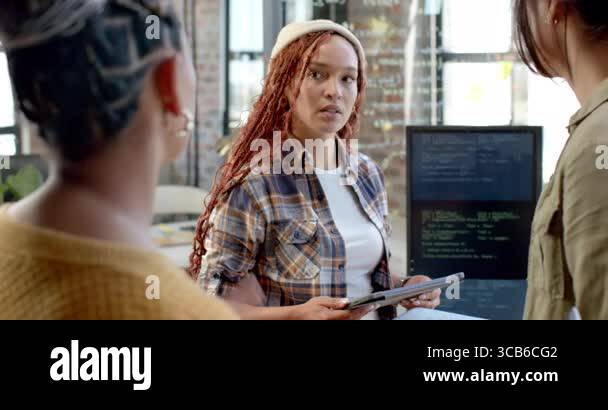 Diverse female team collaborating in modern office, discussing coding project with enthusiasm ...