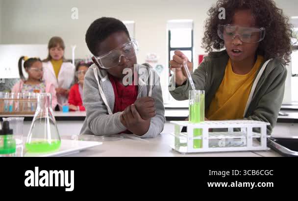 Children conducting science experiment in classroom, using pipette and ...