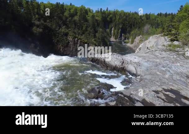 We approach the top of a forest waterfall that plunges into a large pit ...