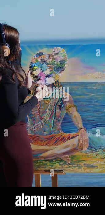 A beautiful woman artist holds a brush, palette in her hands, draws a ...