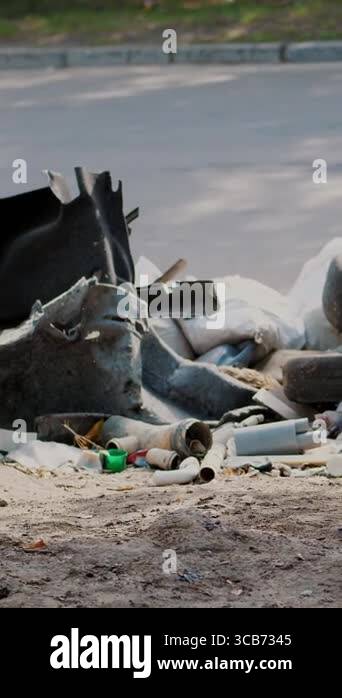 On ground, on side of road, lots of garbage is lying. scattered trash ...