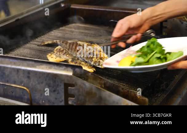 Fresh fish is being grilled at a bustling market while people enjoy ...