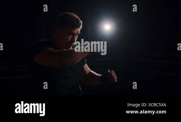 In a dim boxing ring, a determined man displays his skills in an ...