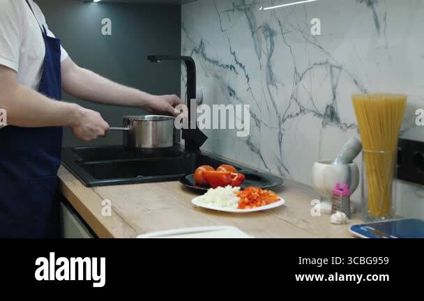 Skilled chef fills a pot with tap water, cooks colorful vegetables and ...