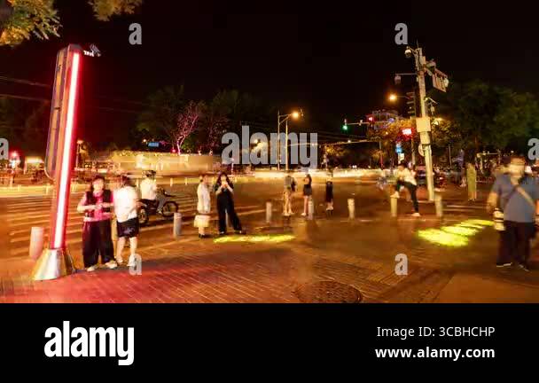 timelapse of pedestrians at night on street with lights and road ...