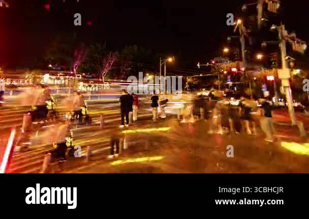 timelapse of pedestrians at night on street with lights and road ...