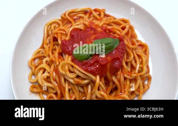 Tagliolini spaghetti pasta with tomato sauce in white plate with basil ...