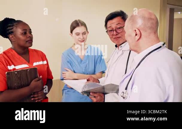 Diverse medical team of doctors and nurses discussing patient records ...