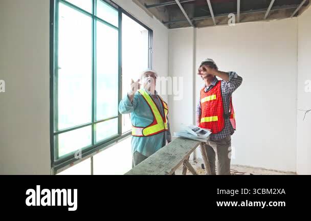 Two construction engineers assess ceiling framework at a building site ...