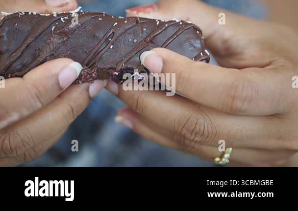 Close-up of hands savoring a chocolate dessert with sprinkles and ...