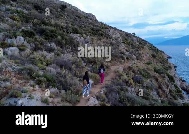 On a Greek island, a narrow hiking trail winds through rocky cliffs ...