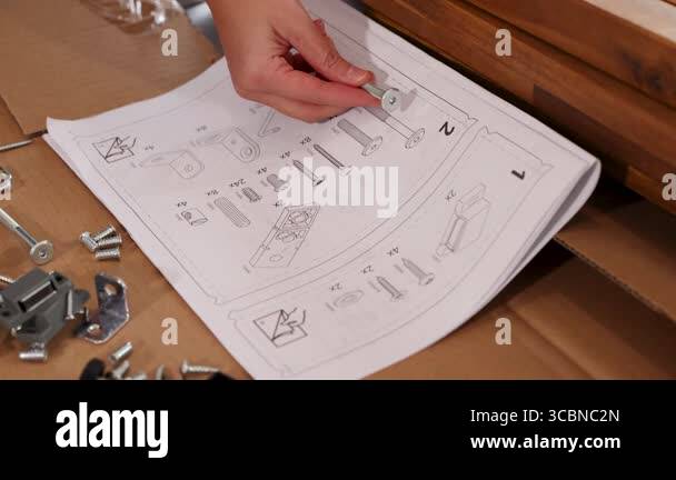 Hands follow detailed instructions to assemble furniture using screws ...