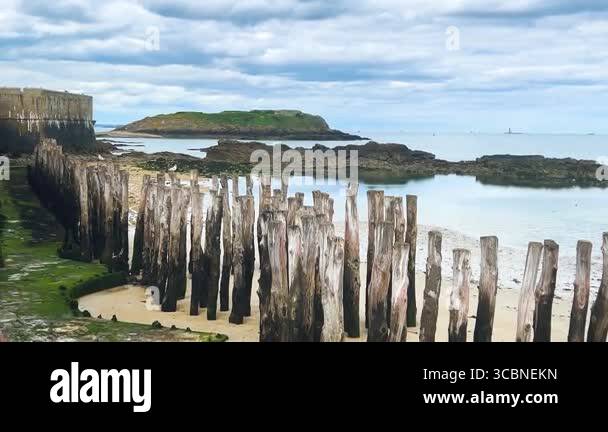 View of wooden pilings breakwaters, rocks, sandy beach of English ...