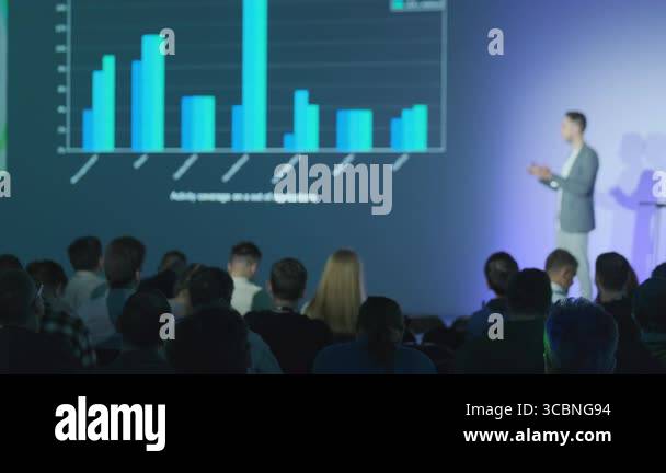 Speaker presenting data visually with graphs to an audience in ...