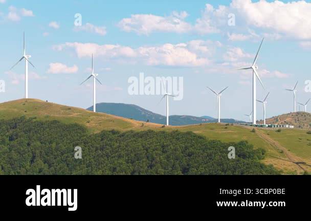 Wide drone shot of multiple wind turbines turning along a mountain ...
