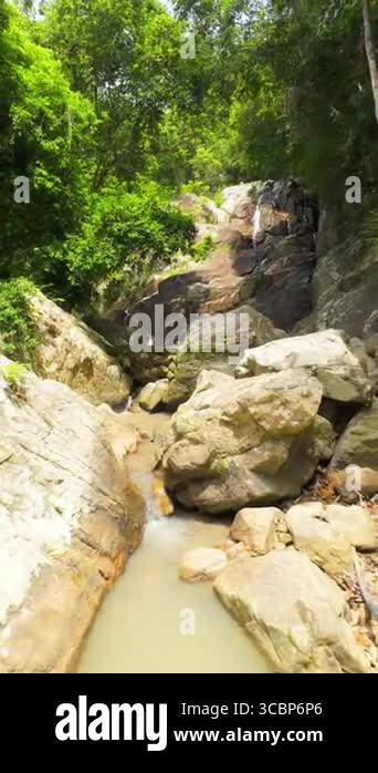 Vertical video. Drone Flying Upstream Through Rocky Jungle Riverbed ...