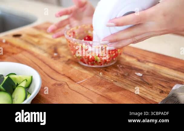 Hands use a manual chopper to finely chop garlic and chili, surrounded ...