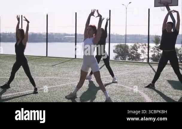 A group of women demonstrates dynamic workout moves on green turf under ...