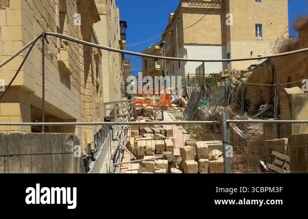 Cluttered urban construction site with limestone blocks, metal fencing ...