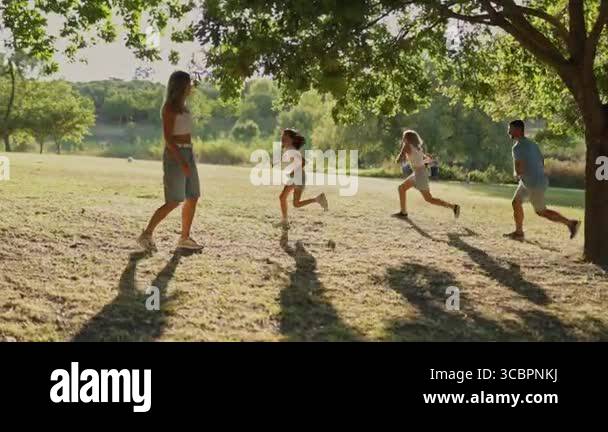 Family enjoying a sunny day playing tag together in a park Stock Video ...
