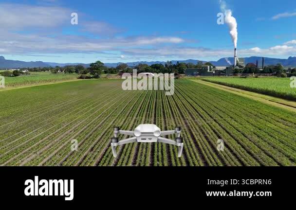 Aerial drone animation over farmland towards a distant factory ...