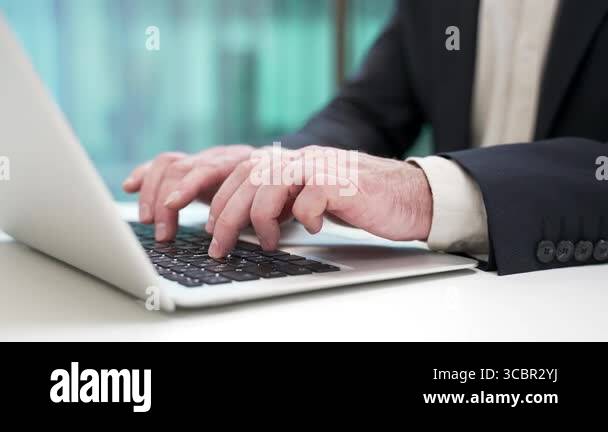 Close up of male hands typing on laptop keyboard in modern office. A ...