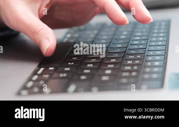 A close-up shot of a hand typing on a laptop keyboard, emphasizing ...