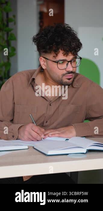Young student writing detailed notes in notebook while studying ...