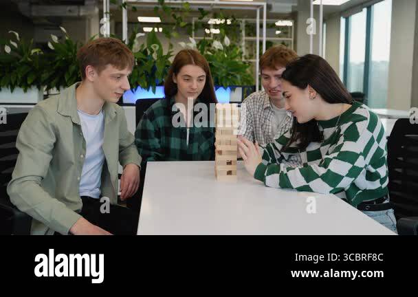 Caucasian students enjoy a lively game of jenga, carefully removing ...
