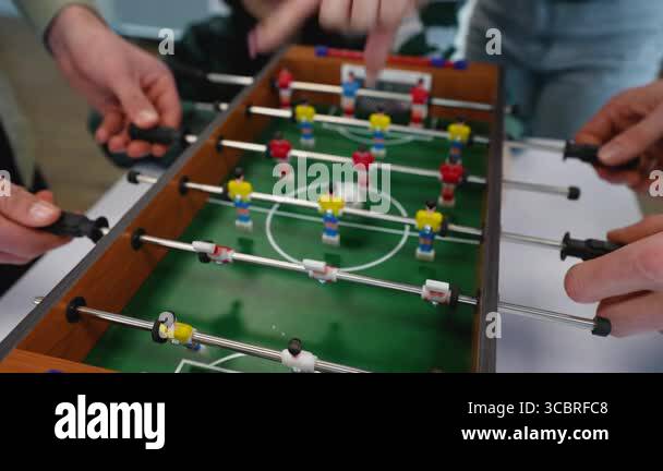 Caucasian teenage students enjoy a friendly foosball match, their hands ...