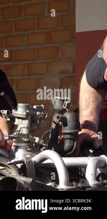 Vertical closeup of hands adjusting vintage motor parts with meticulous ...