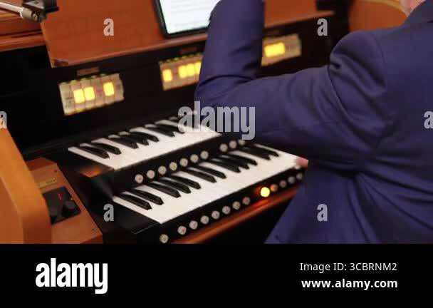 A close-up of a man playing a church organ, his hands gracefully ...