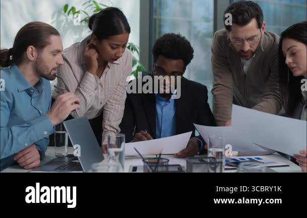 Multicultural business team African American Caucasian Indian women men in office talking ...