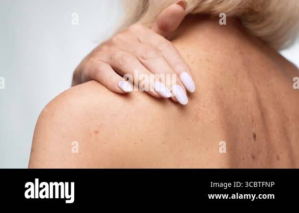 An elderly woman in her 60s practices pampering her skin at home. Her ...