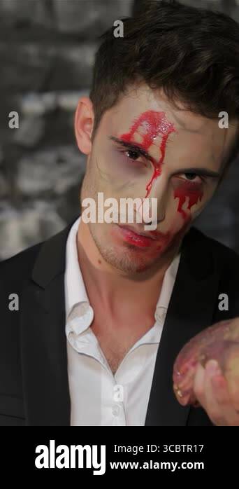 A captivating vampire, clad in a sleek black suit, grips a gruesome ...