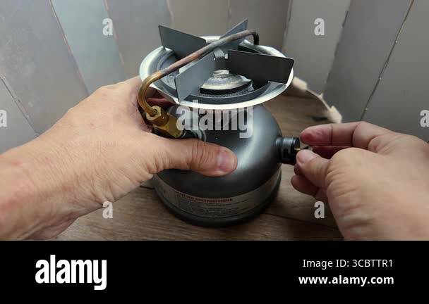 A person prepares a portable camping stove for outdoor cooking. The ...