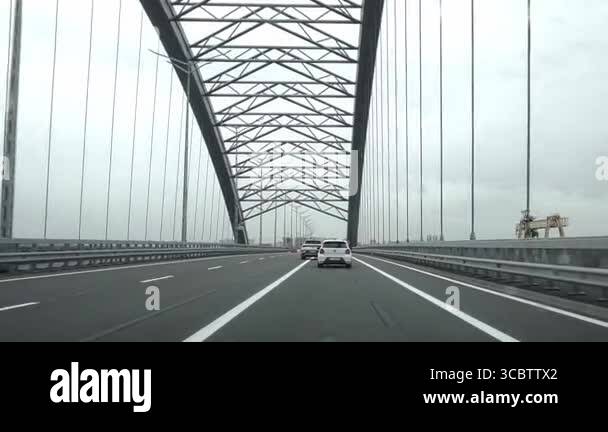 Point of view footage from a car driving across a modern steel bridge ...