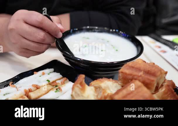 Person eating congee with deep-fried dough sticks Stock Video Footage ...