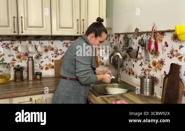 Young woman doing household chores at home, staying productive and organized. She handles daily ...